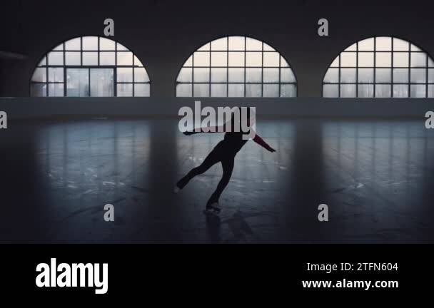 Little girl skater glides on skates on a dark ice arena. Young athlete ...