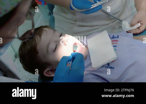 Woman dentist examines baby teeth of child little boy patient in clinic ...