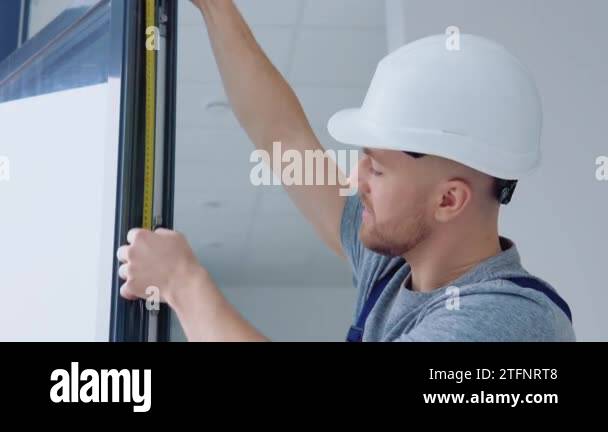 Window installer measures the dimensions of the window frame with a ...