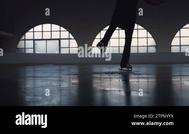 Young woman is skating on dark ice arena. Close up of female legs in ...