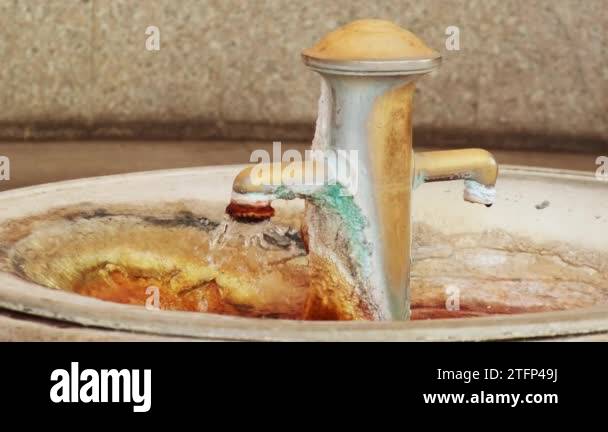 Medieval faucet pouring healing water into deep stone basin in Karlovy ...