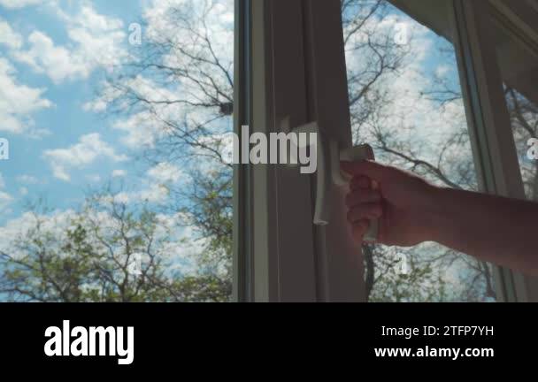 A man's hand opens a window to ventilate the room. Outside the window ...