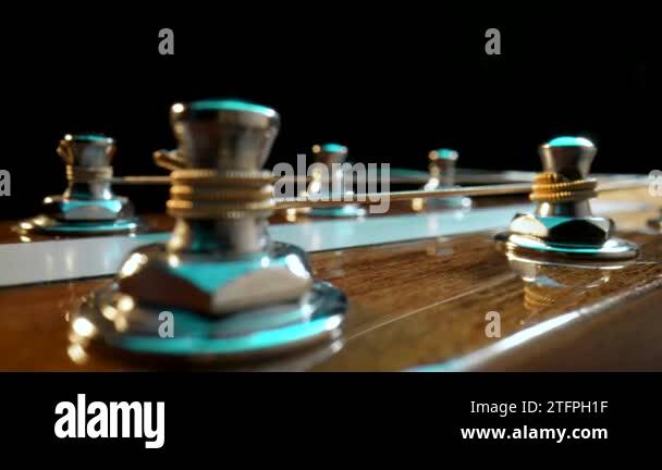 Wooden guitars headstock with metal tuning pegs and string on a black ...