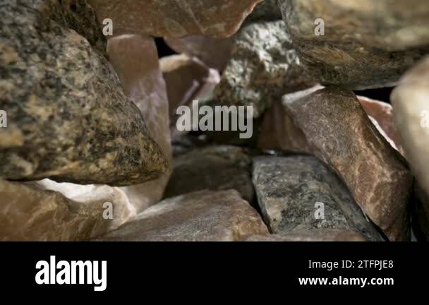 Camera pans inside a pile of gray and brown granite stones against a ...