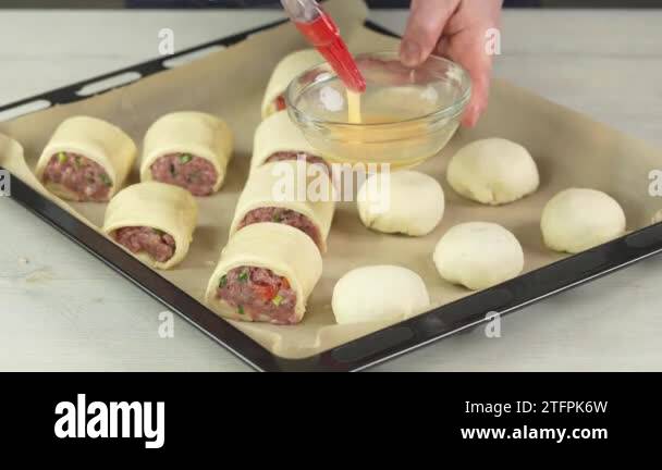 smearing egg pies on baking sheet. Cooking stuffed pies. woman smearing ...