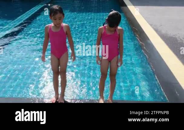 Happy little sisters play in outdoor swimming pool of tropical resort ...