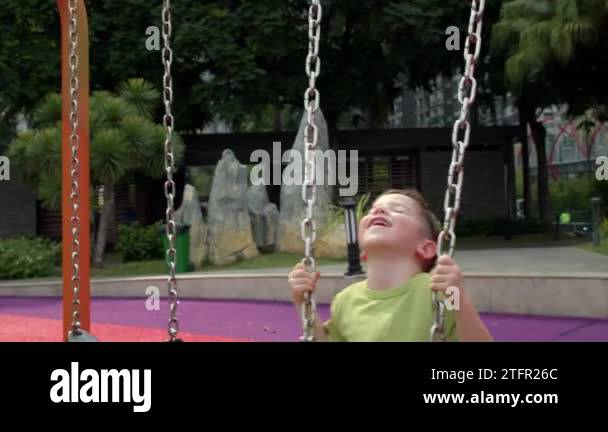 Happy laughing child swings on a swing in the park little boy, on a ...