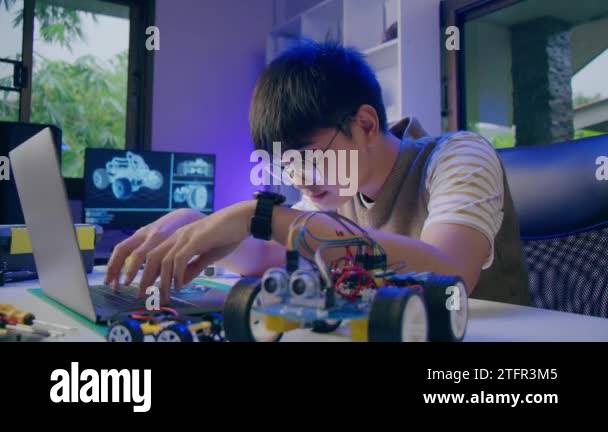 Asian teenager doing Arduino robot homework project in house, technology of robotics programing ...