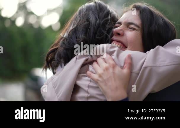 Two female friends hug and embrace outside real life happiness reunion ...