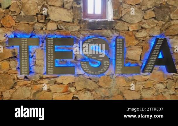 Tesla logo with blue lighting on brick wall inside Nikola Tesla ...
