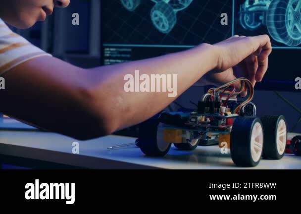 Asian teenager doing Arduino robot homework project in house, technology of robotics programing ...