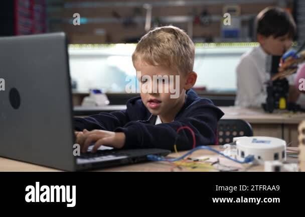 Portrait of smart cute little boy programming software for robotics at ...