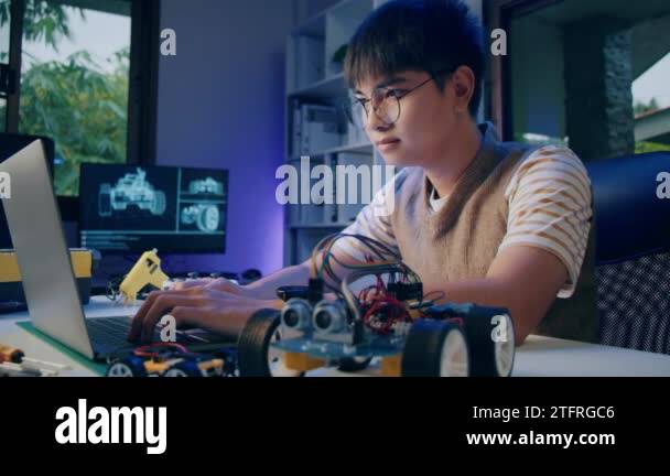 Asian teenager doing Arduino robot homework project in house, technology of robotics programing ...