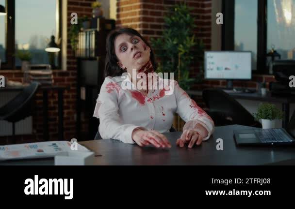 Scary looking office zombie with deep and bloody scars sitting at table ...
