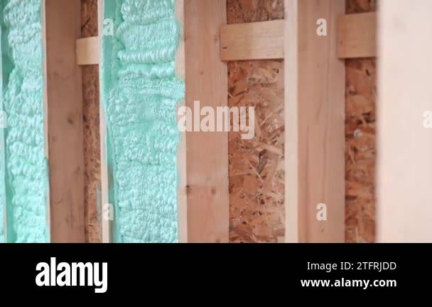 Male builder insulating wooden frame house. Man worker spraying ...