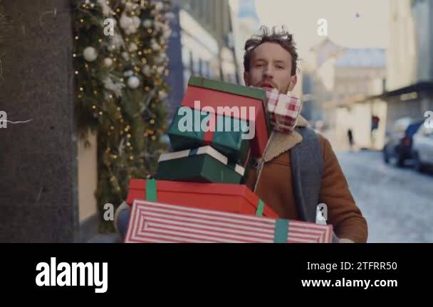 Man is hurry up , running on the street holding many christmas gifts ...