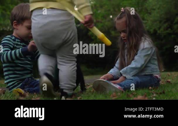 Friends play with Toys Excited young children playing lying on grass ...