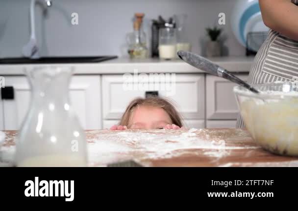 fun cooking, little girl having fun and peeking out from under table ...