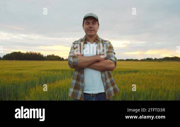 Farmer in front of a sunset agricultural landscape. Man in a ...