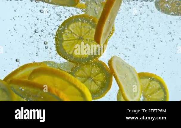 Cut juicy lemon floating in crystal water with air bubbles close up ...