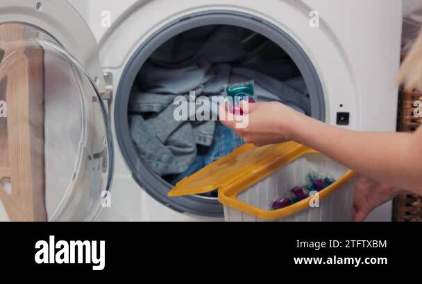 The woman sits at the washing machine and performs household chores ...