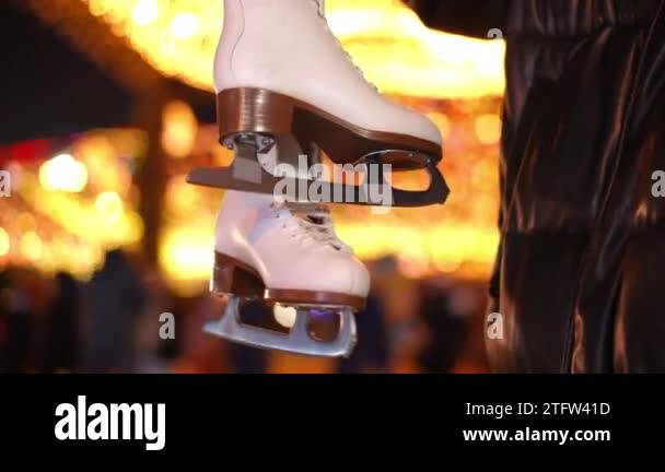 Close-up white ice skates at background of Christmas lights in urban ...