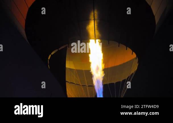 Close-up of balloon at night as it inflates for flight, burning burner ...