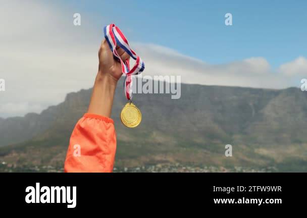 Success, female hand holding gold medal against the dramatic sky ...