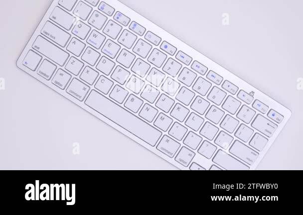 White metallic small keyboard rotating and seen from top down spinning ...