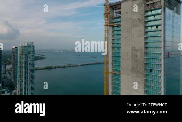 Fly around construction of new skyscraper. Revealing panoramic view of sea bay and aircraft in ...