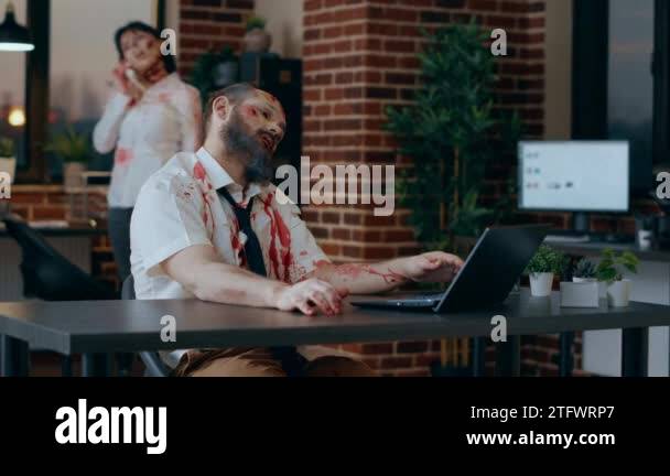 Scary looking zombie trying to work on modern laptop in office ...