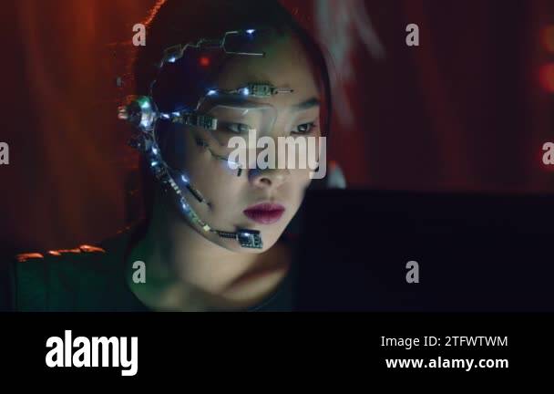 A Cyberpunk girl works on the computer in the red neon lights. Asian ...