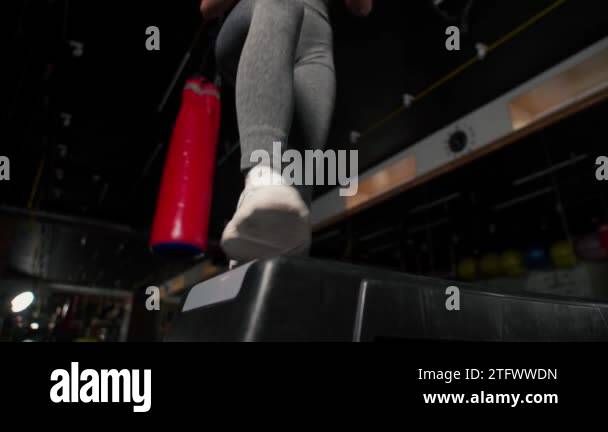 female legs in sports shoes perform stepping on an elevated step ...