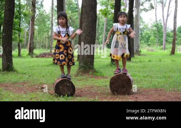 Cute kids playing in outdoor park. Little sisters stand on logs playing ...