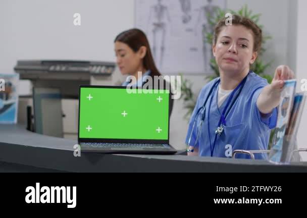 Nurse and receptionist working with greenscreen on laptop at facility ...