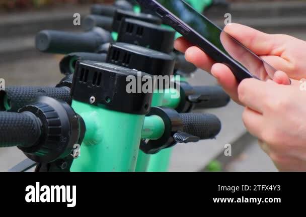 Woman using app on smartphone to unlock electric scooter on the street ...