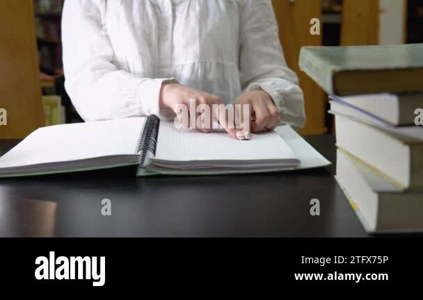 Blind girl reading a text of Braille in library. Braille is a tactile ...