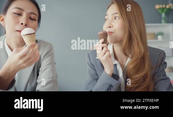 Group of young asia creative team workers enjoying having fun talking laughing eating ice cream ...