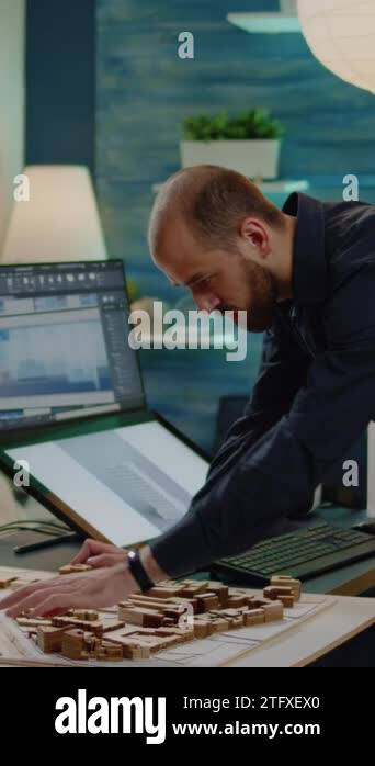 Vertical video: Man with architect job working on building model with ...