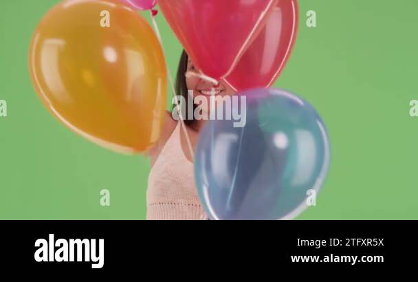 Millennial Latina girl popping her balloons on green screen. On green ...