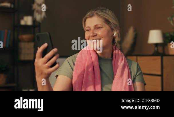Retired woman sits on exercise ball in living room and makes video call ...