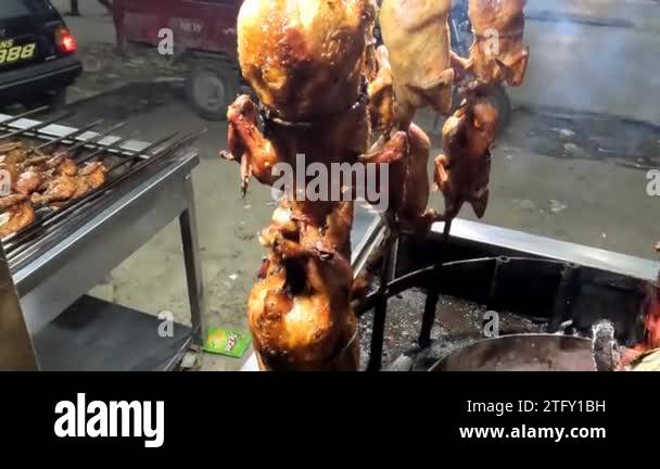 Chicken roasted on spit being grilled over the bright glowing beech ...