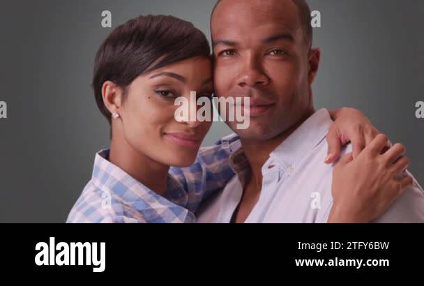 African American couple pose for a portrait on a grey gradient ...