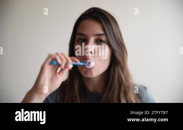 Young beautiful woman brushes her teeth with a toothbrush in the ...