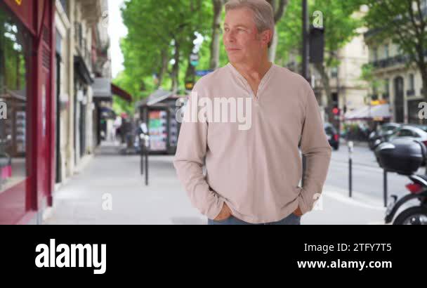 Bold older white man looks around on a Paris sidewalk then turns ...
