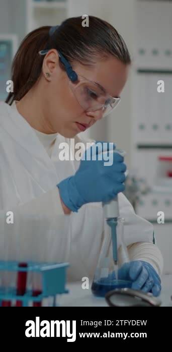 Vertical video: Lab worker using micro pipette with beaker and test ...