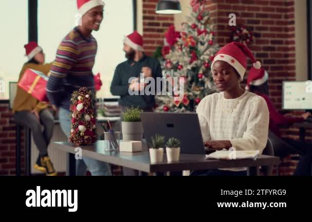 Colleagues with santa hats exchanging presents during xmas eve, giving ...
