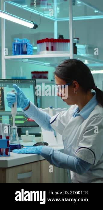 Vertical video: Scientist woman pipetting liquid to test tube working ...