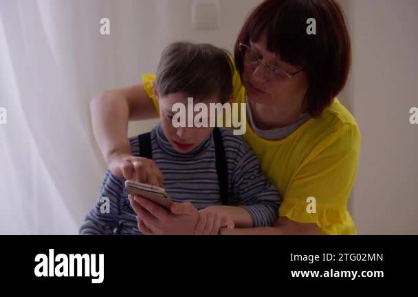 Caucasian mother hugging autistic son showing games on smartphone ...