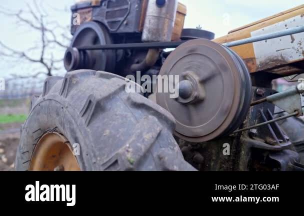 Working process of rotating pulley with belt. Man works in garden with ...